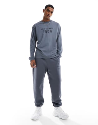 New Balance – Iconic – Trainingsanzug in Grau mit College-Print | ASOS