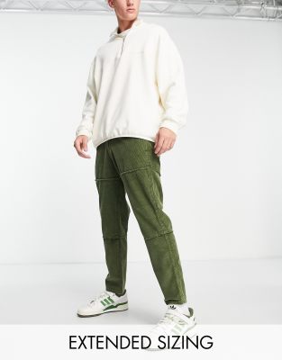 ASOS DESIGN tapered corduroy pants with busted seams in green | ASOS