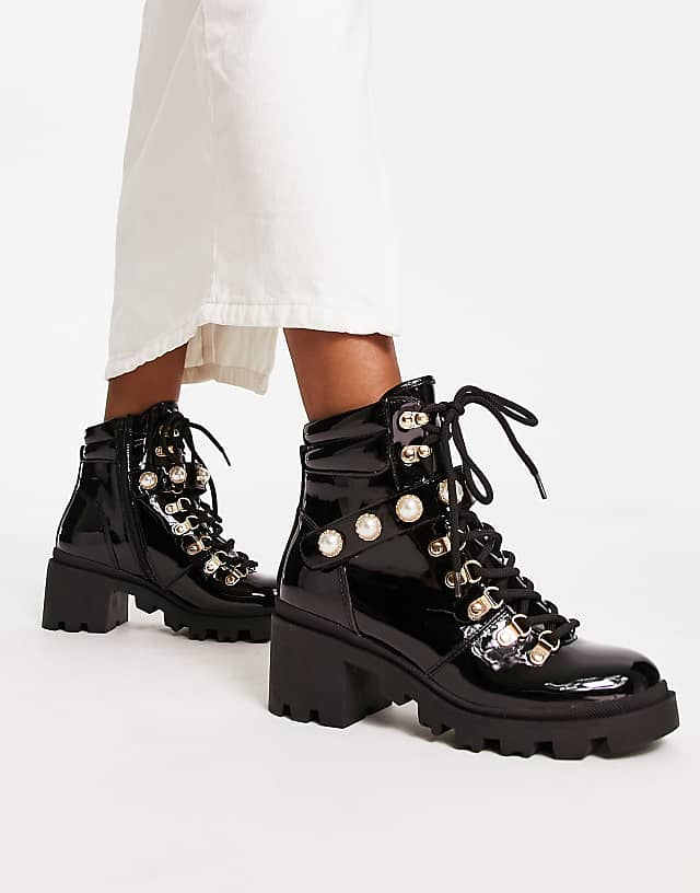 Botas negras de estilo montañero de charol con tacón y detalle de ... Botas negras de estilo montañero de charol con tacón y detalle de ...