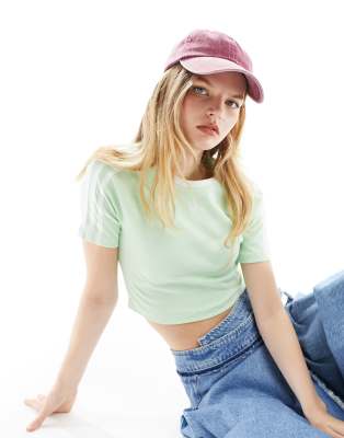 Camiseta verde pastel con diseño encogido y detalle de tres rayas de ...